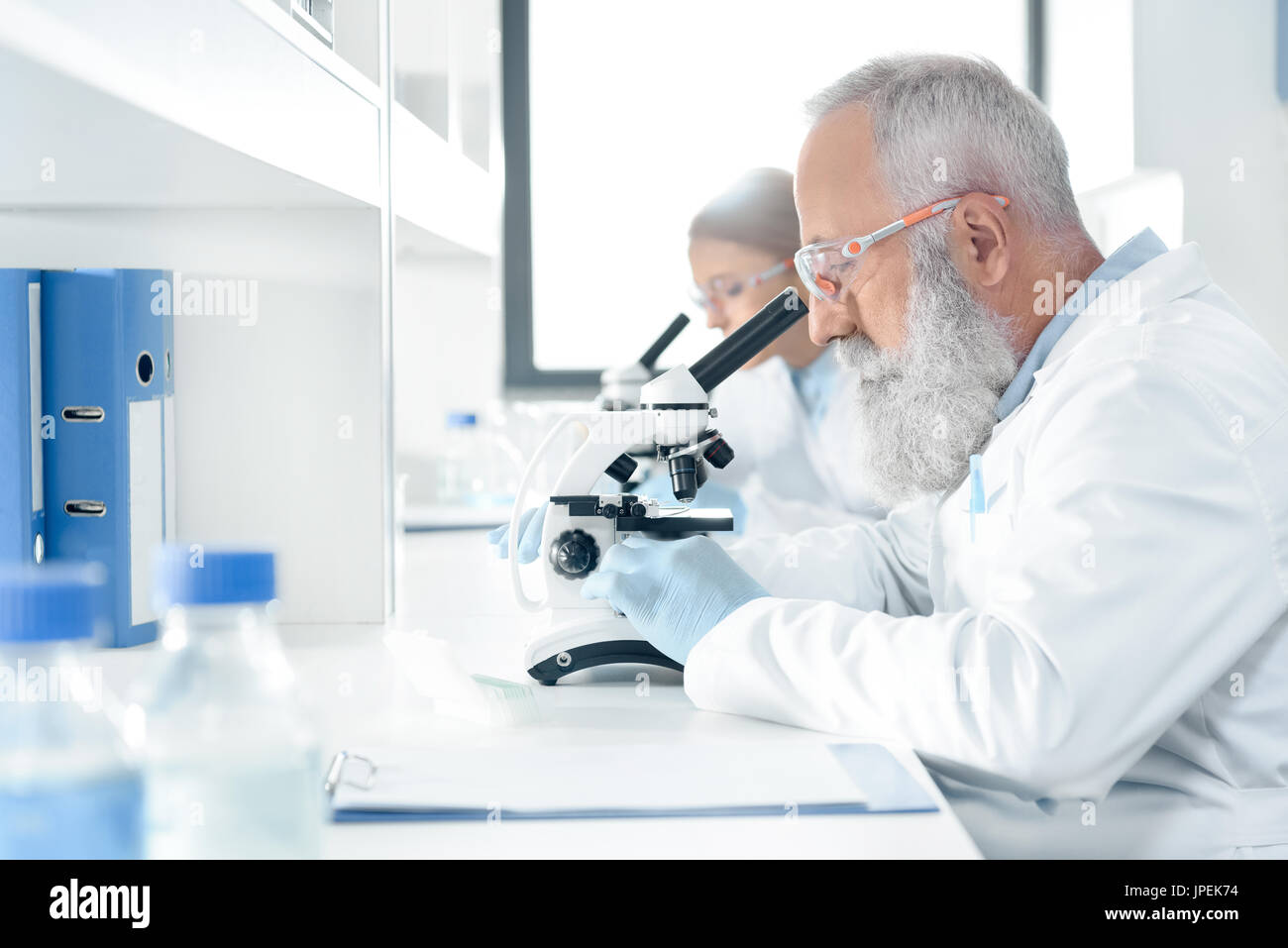 Side view of scientists in white coats working with microscopes in chemical lab Stock Photo - Alamy