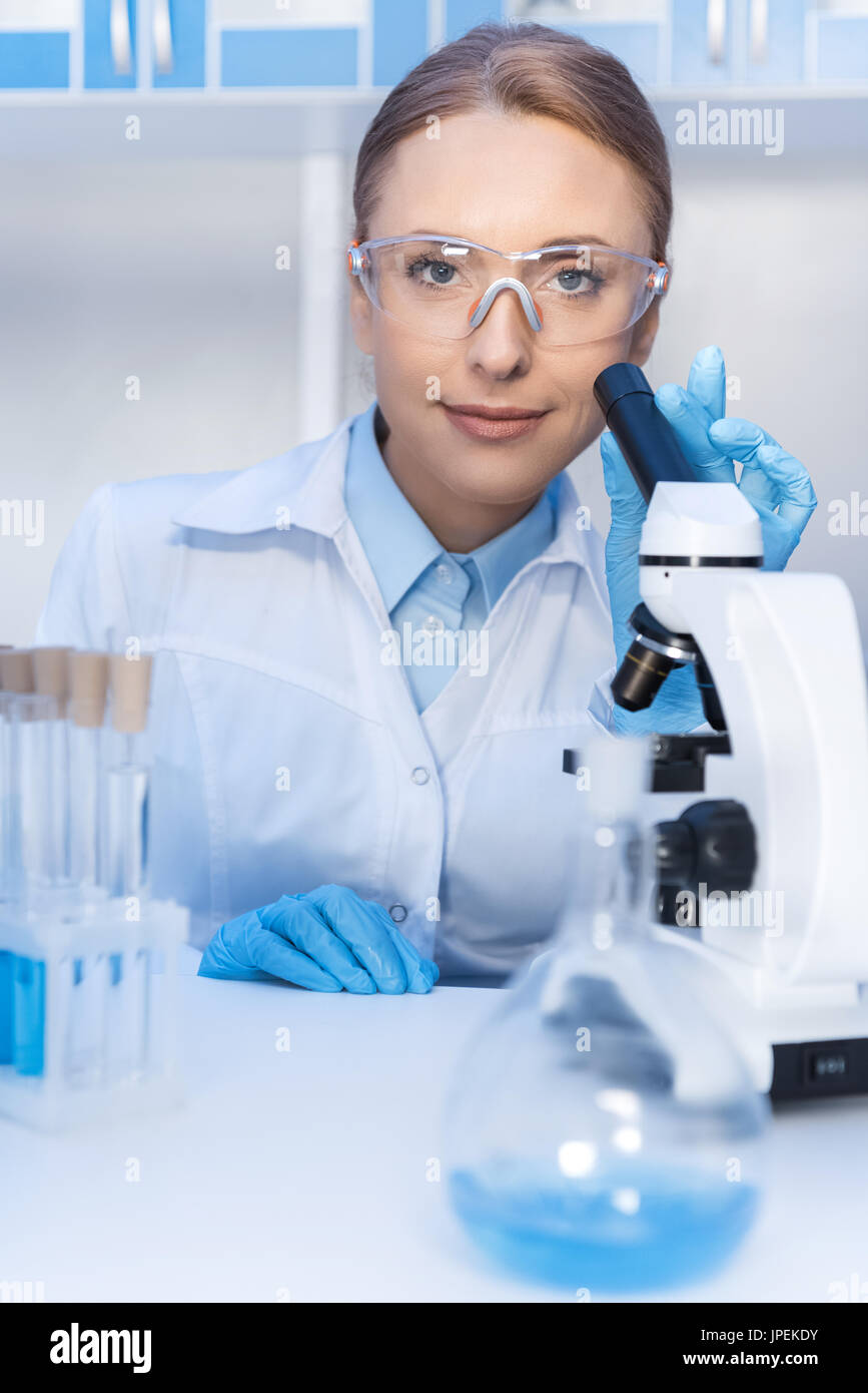 portrait of smiling scientist using microscope while working with ...