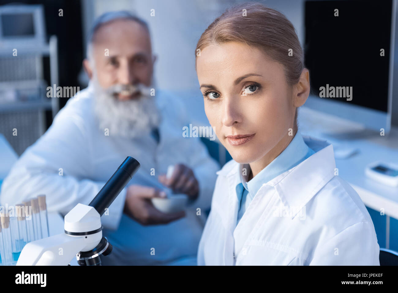 two scientists in lab coats looking at camera while working at ...