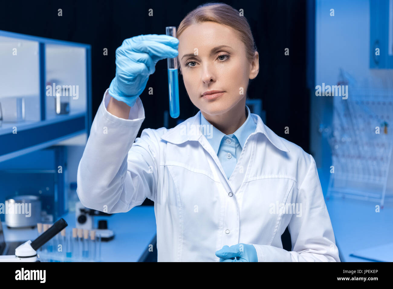 pensive laboratory technician looking at tube with reagent at ...