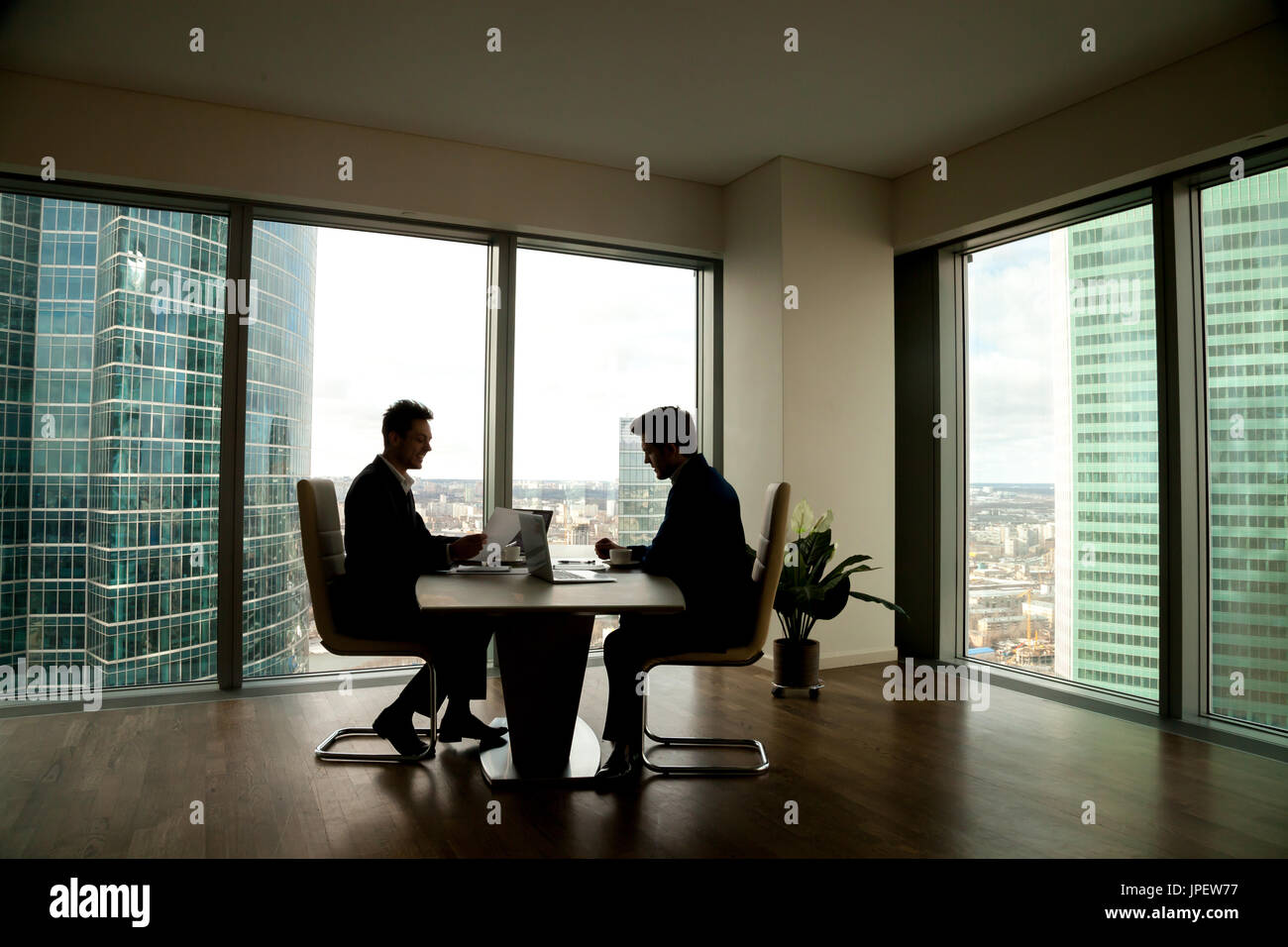 Two businessmen negotiating sitting at conference table in moder Stock ...