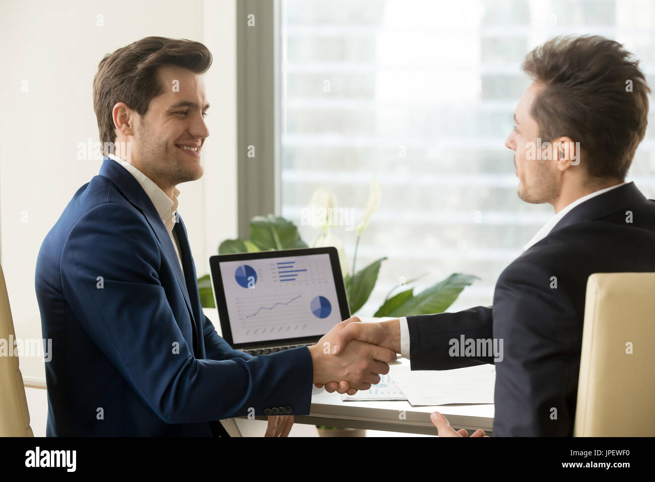 Two smiling businessmen handshaking, partners satisfied with fin Stock ...