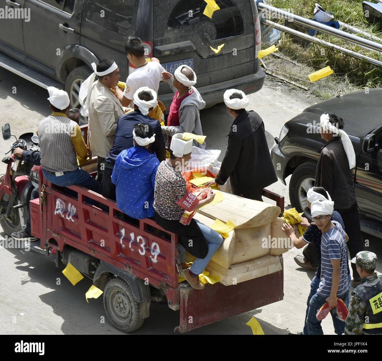 Members of a funeral procession throw yellow joss paper in the air as a ...
