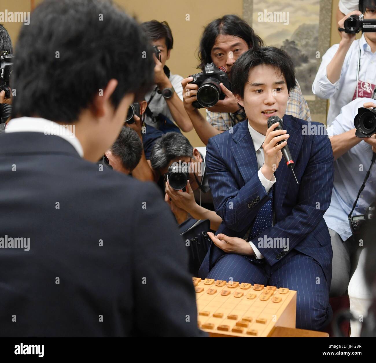 Yuki Sasaki (facing camera), a professional player of shogi Japanese chess, comments after ...
