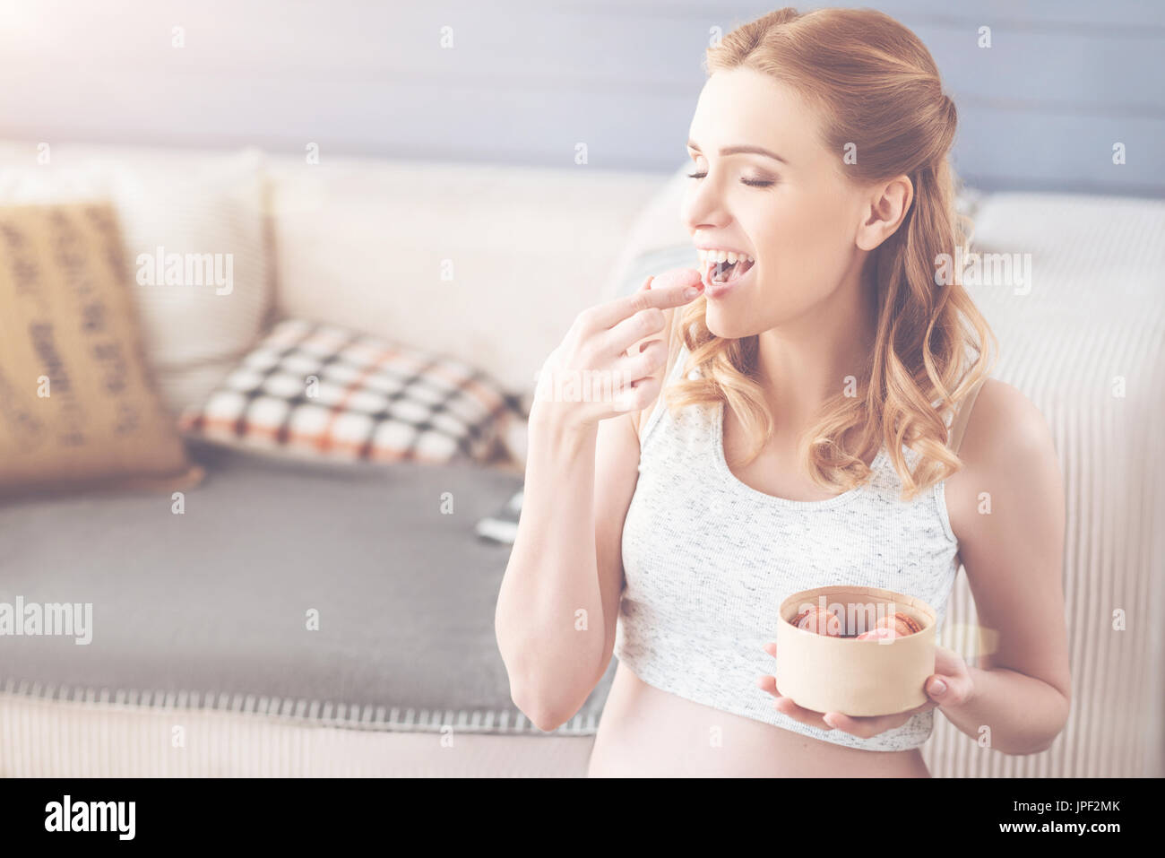 Positive young pregnant woman eating macaroons Stock Photo - Alamy