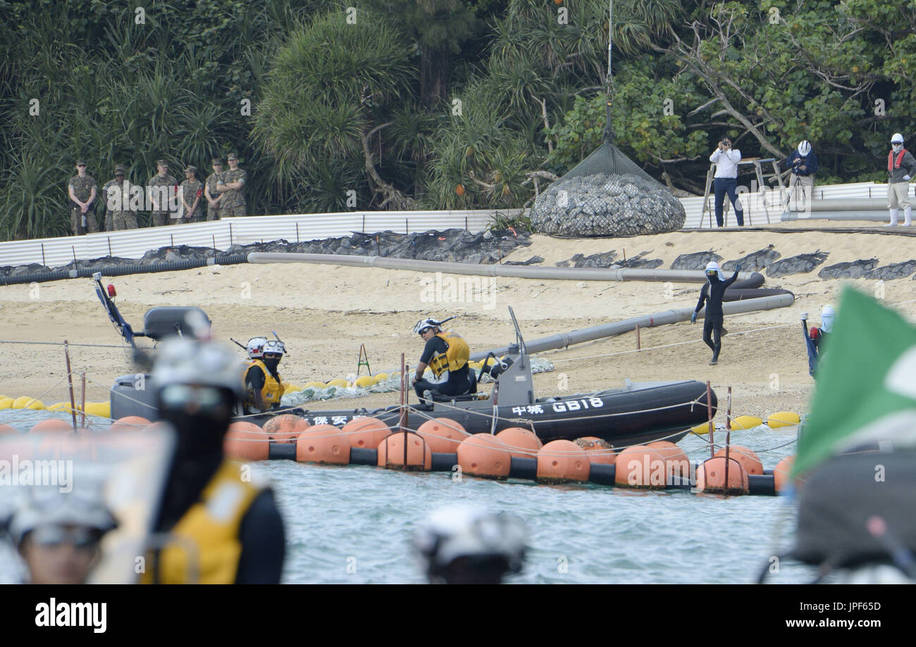 With Japan Coast Guard officials keeping guard, a crane lowers stones ...