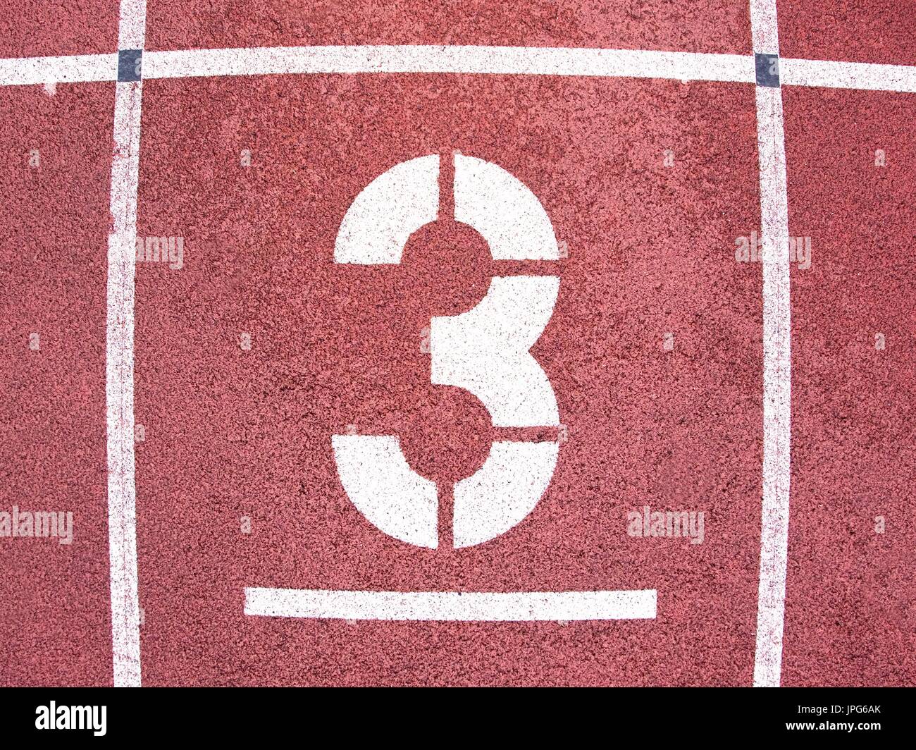 Number three. White track number on red rubber racetrack, texture of ...