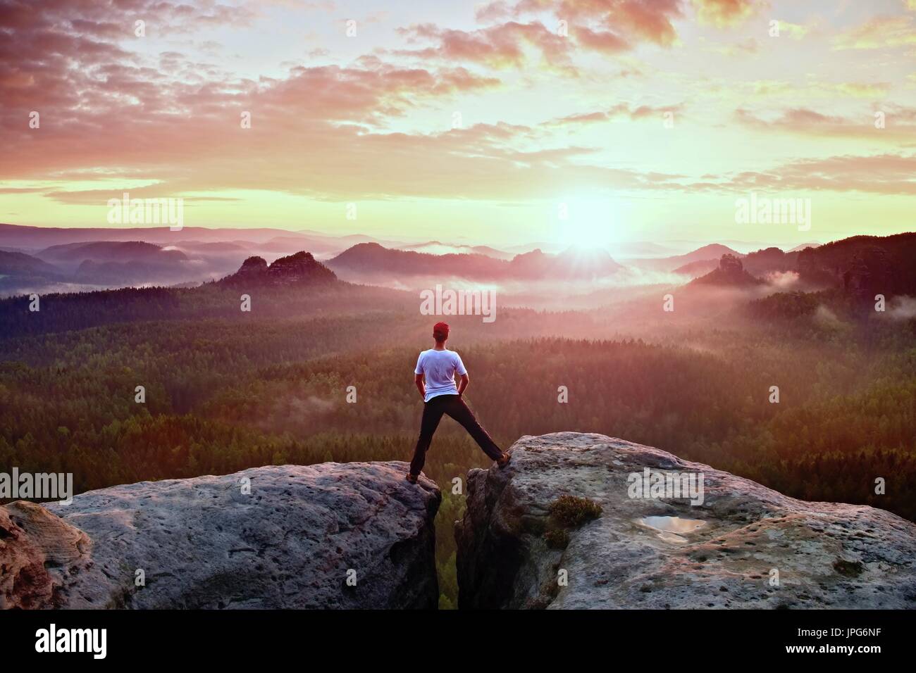 Crazy jumping hiker in black celebrate triumph between two rocky peaks ...