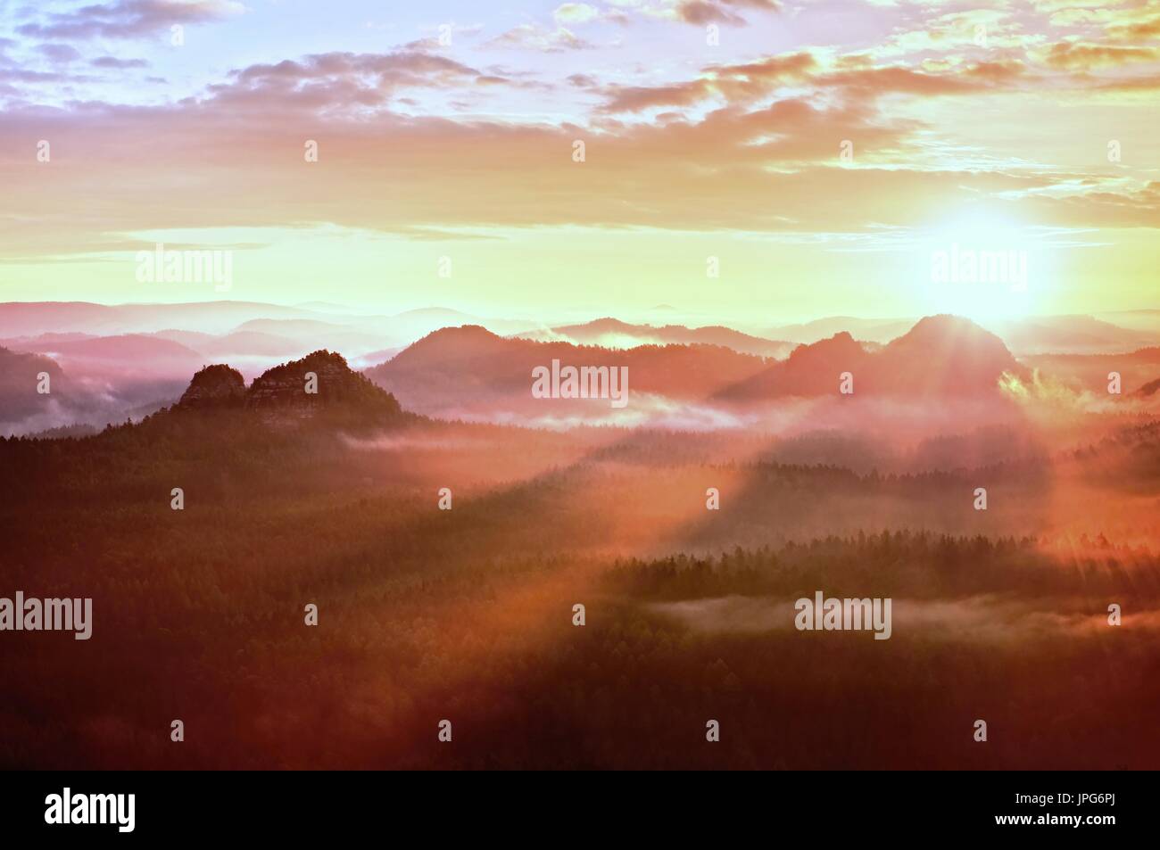 Red misty daybreak. Foggy autumn morning in a beautiful hills. Peaks of hills are sticking out ...