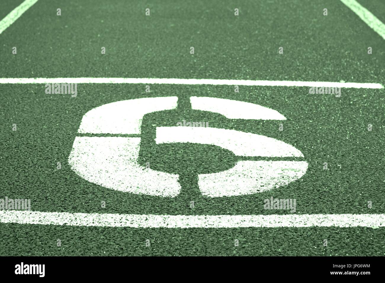 Number six. White athletic track number on red rubber racetrack ...