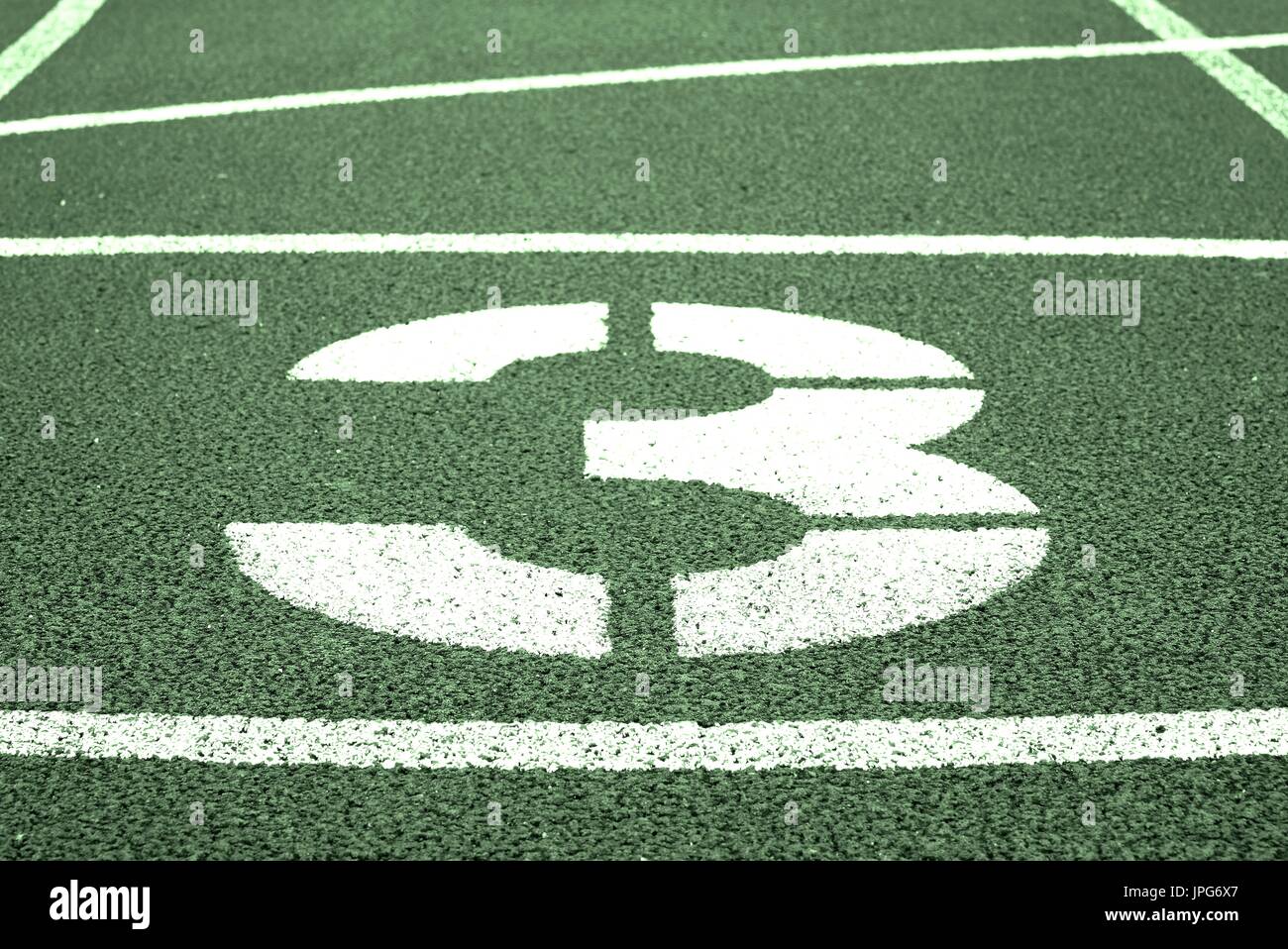 Number three. White track number on red rubber racetrack, texture of ...