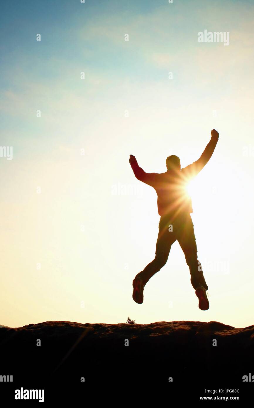 Jumping man. Young crazy man is jumping on colorful sky background ...