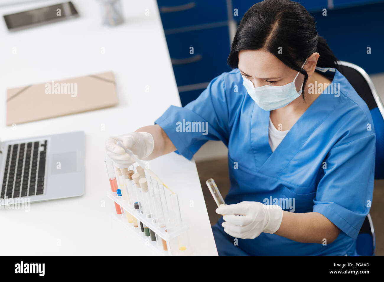 Nice pleasant chemist sitting at the table Stock Photo - Alamy