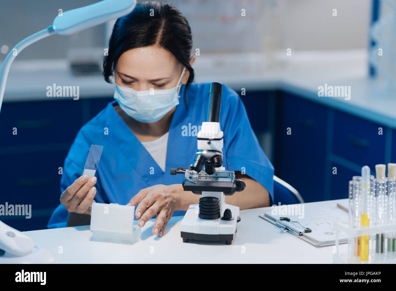 Smart nice biologist holding a microscope slide Stock Photo - Alamy