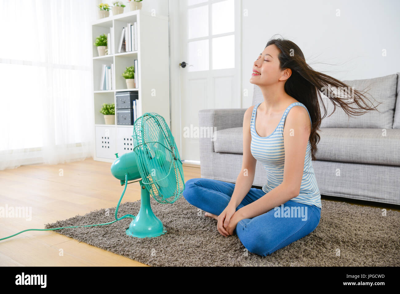 beauty young woman sitting on living room and using electric fan ...