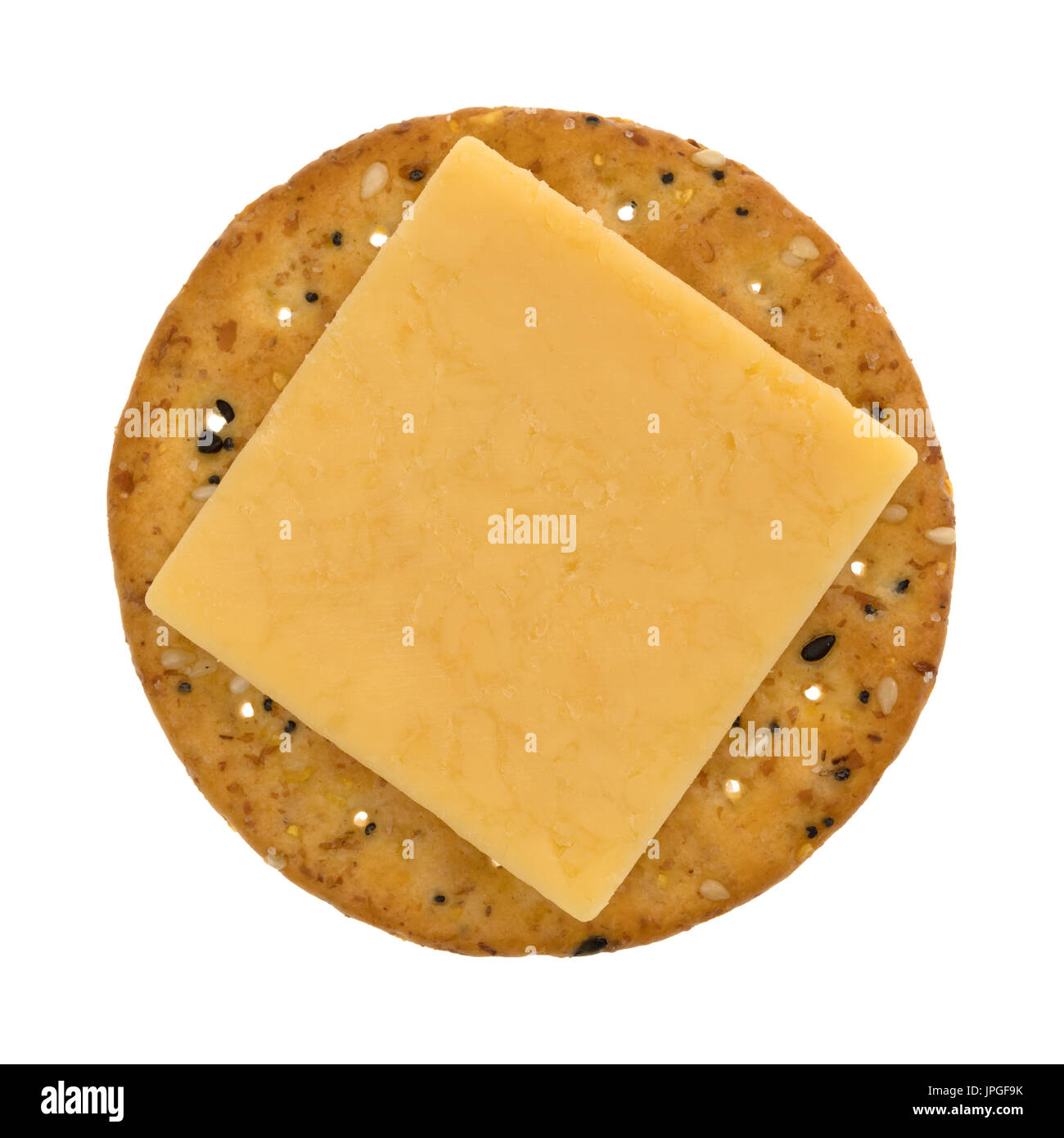 A square slice of gouda cheese on a round multi grain cracker isolated ...