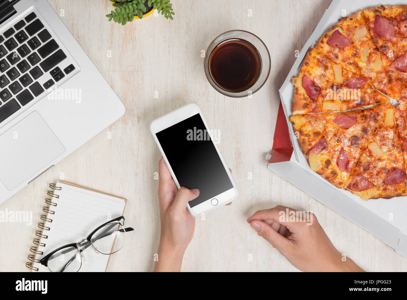 Hands ordering pizza with a device over a wooden workspace table Stock ...