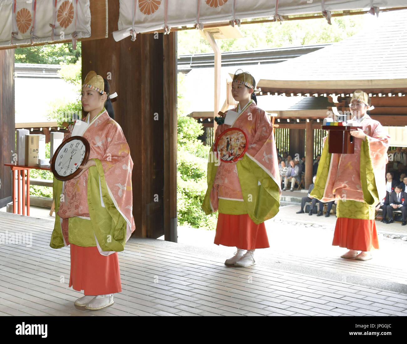 Women clad in ancient Japanese court dresses hold timepieces during an ...