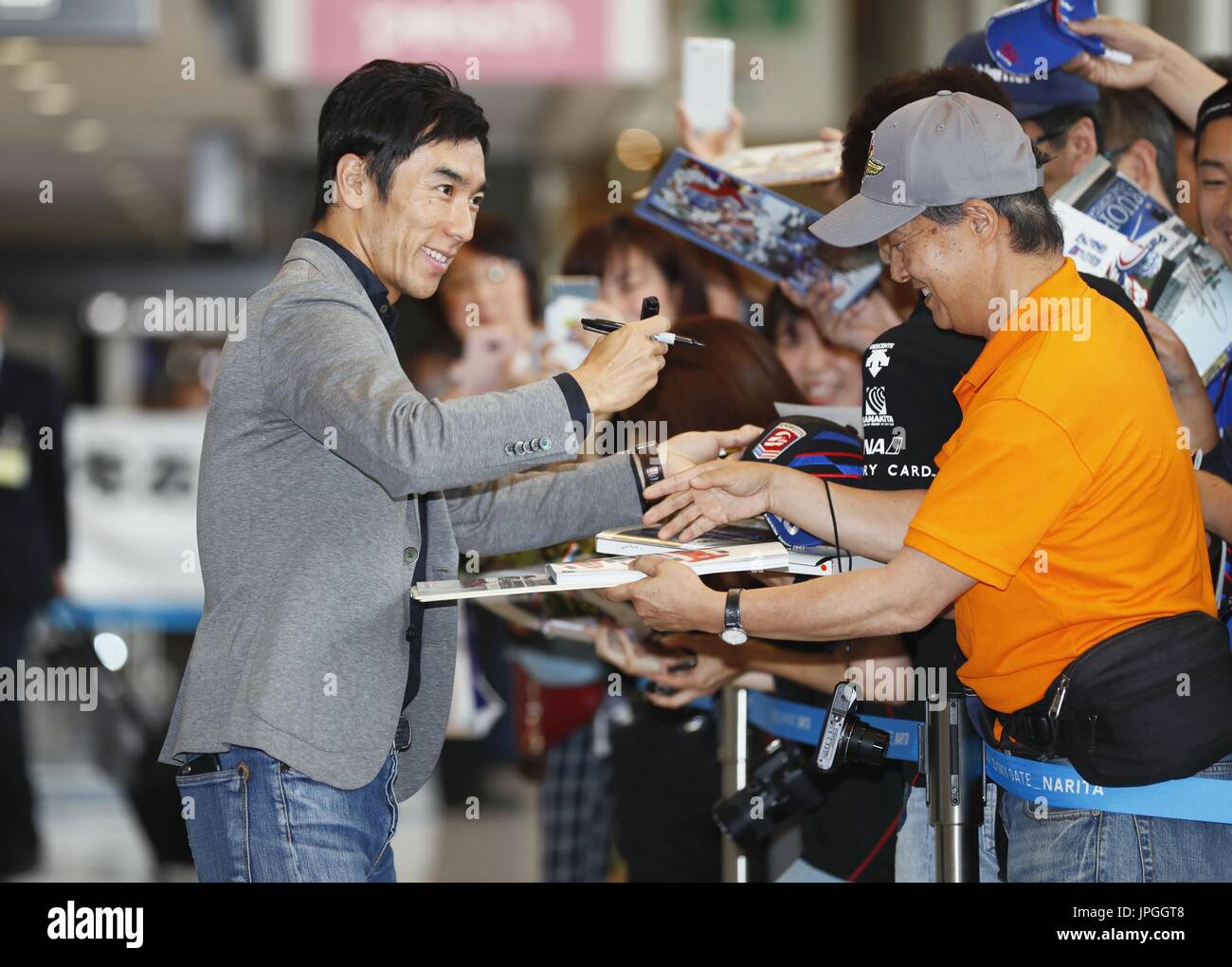 Indianapolis 500 champion Takuma Sato (L) of Japan signs an autograph ...