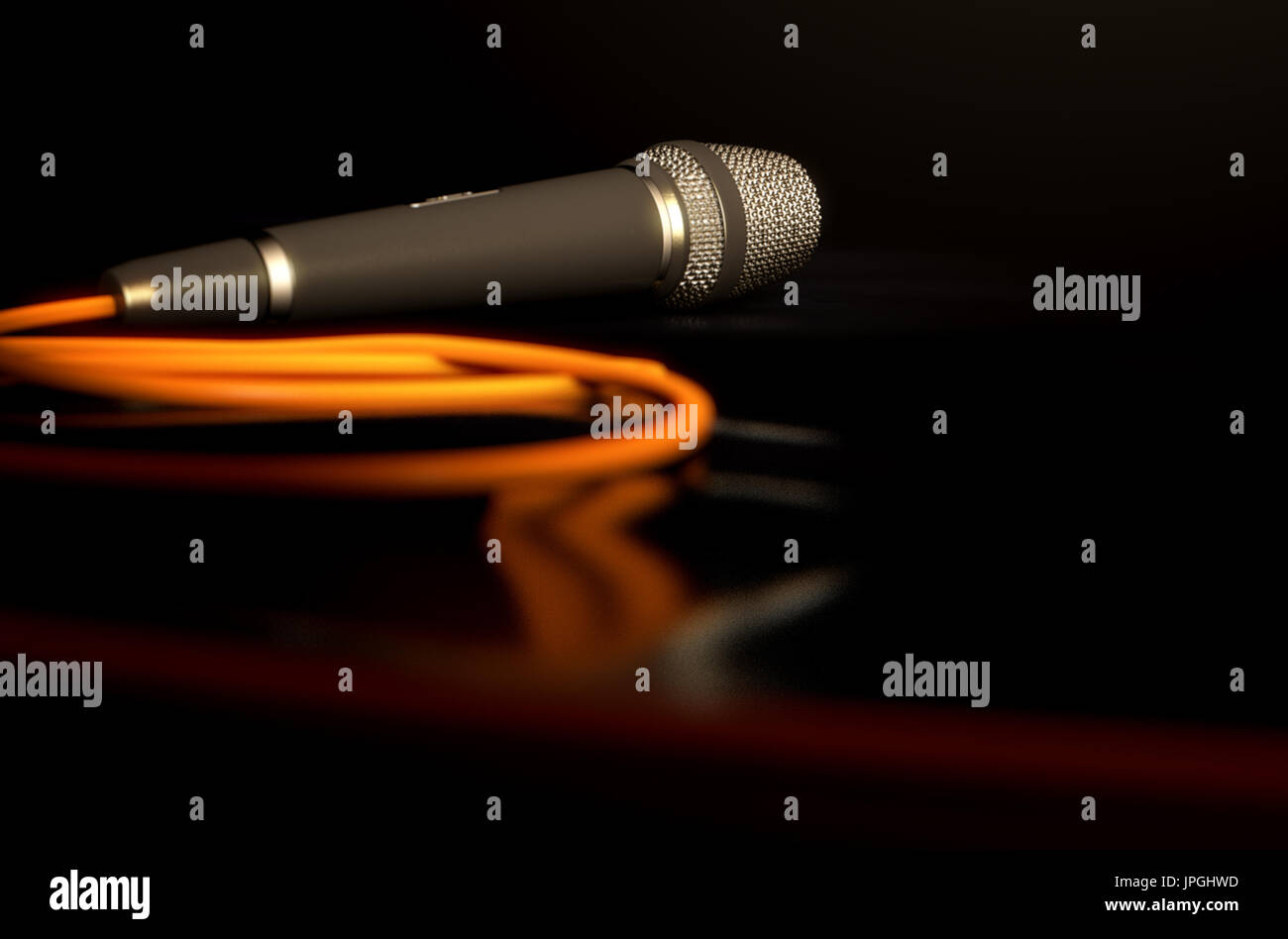 A black metal microphone on laying on a dark stage floor with its cord ...