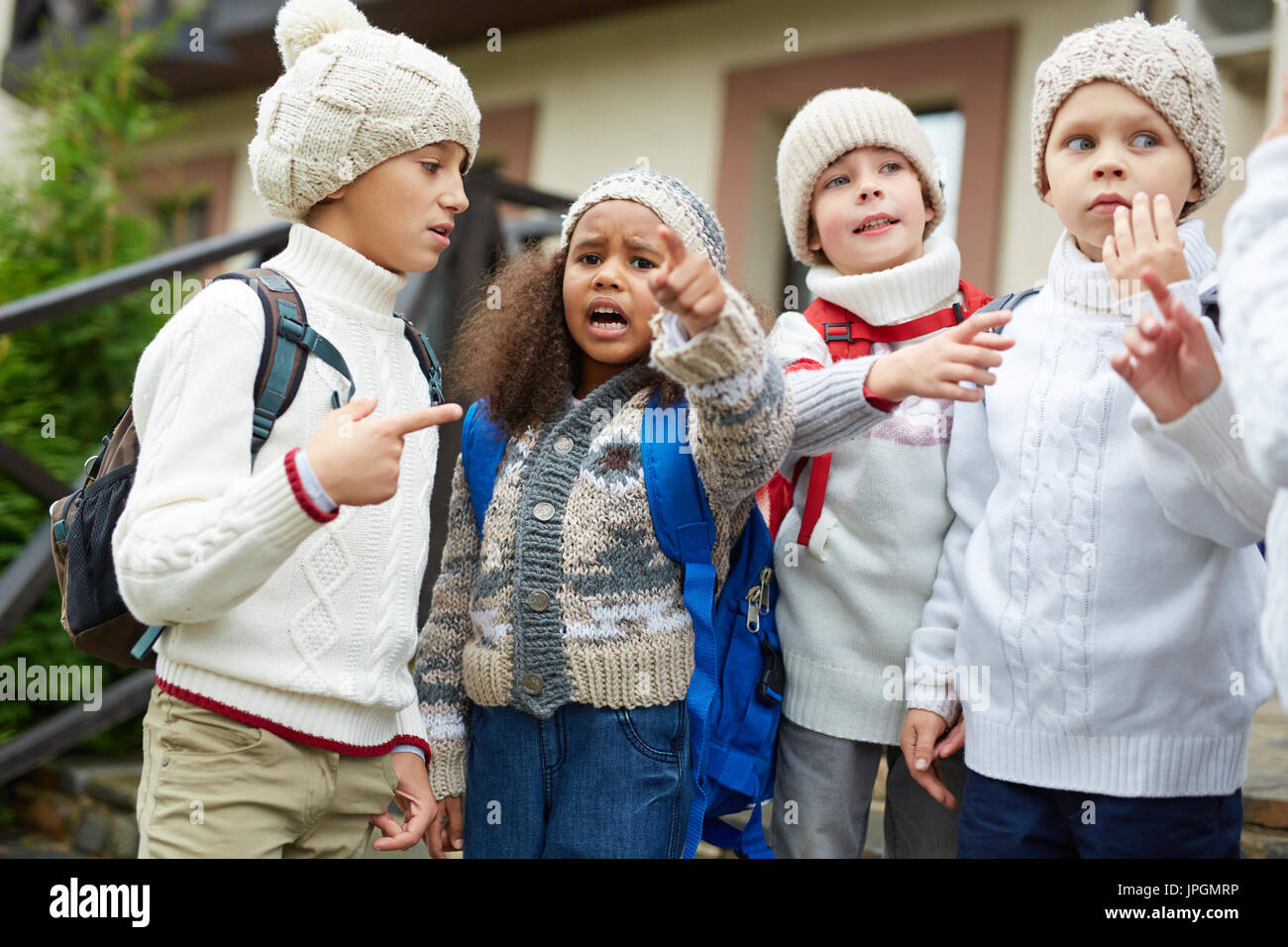 Group of little kids with rucksacks having talk after classes Stock ...