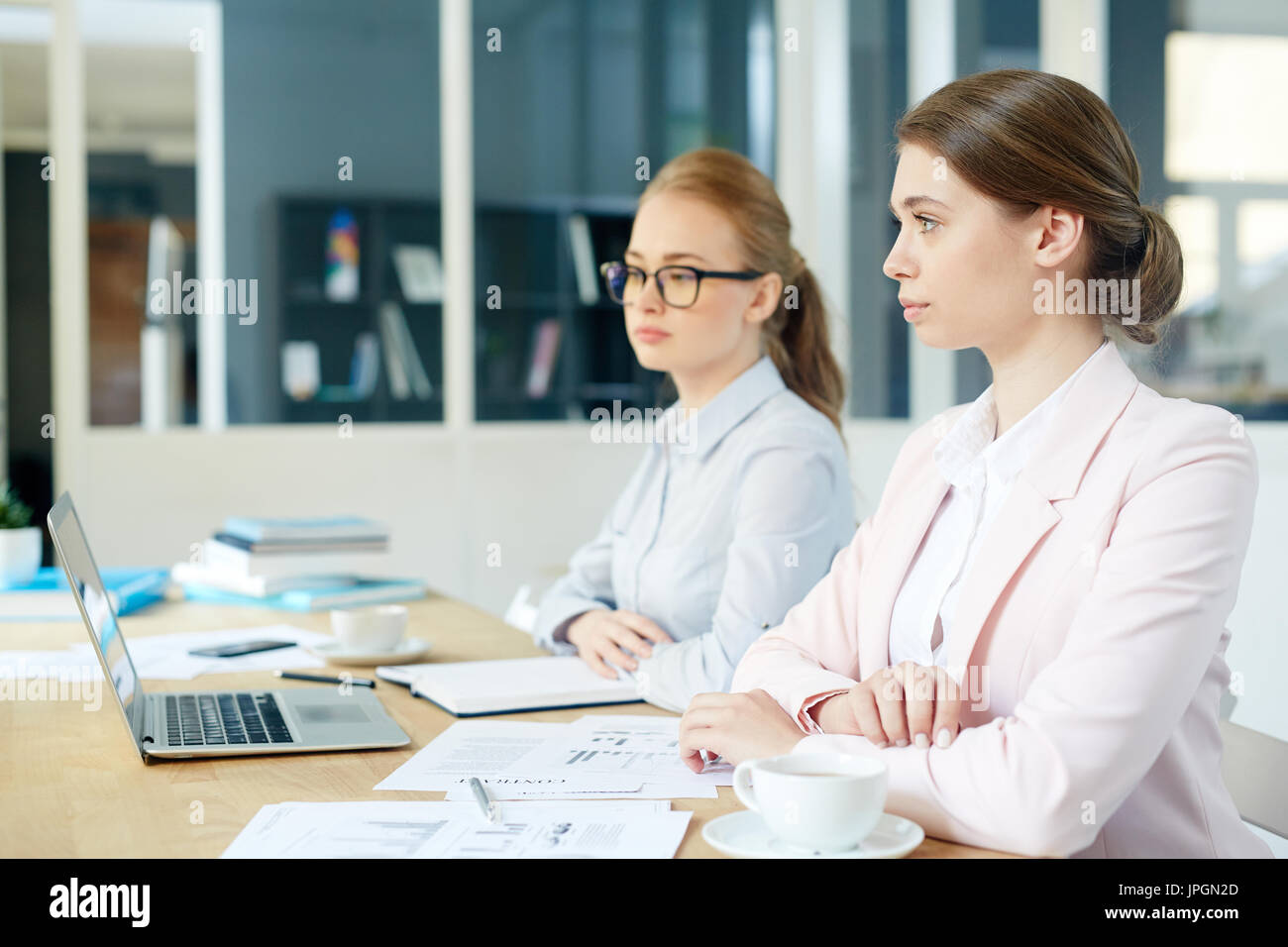 Two girls sitting by desk at briefing Stock Photo - Alamy