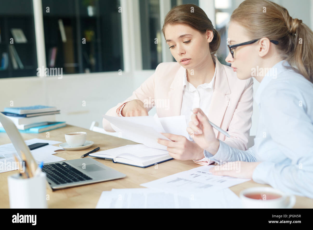 Intellectual women looking through business papers at workplace Stock ...