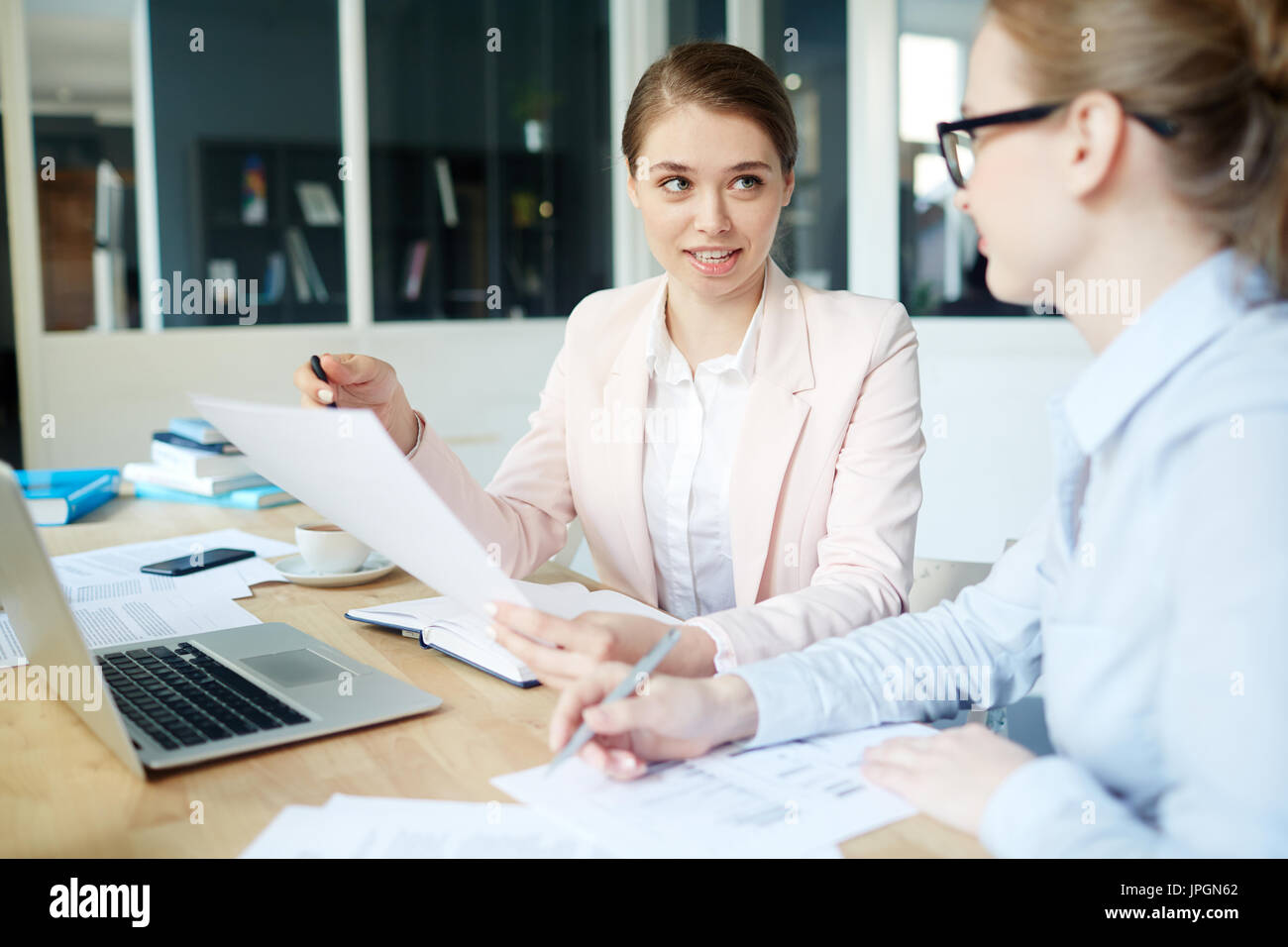 Young economist explaining information to her colleague Stock Photo - Alamy