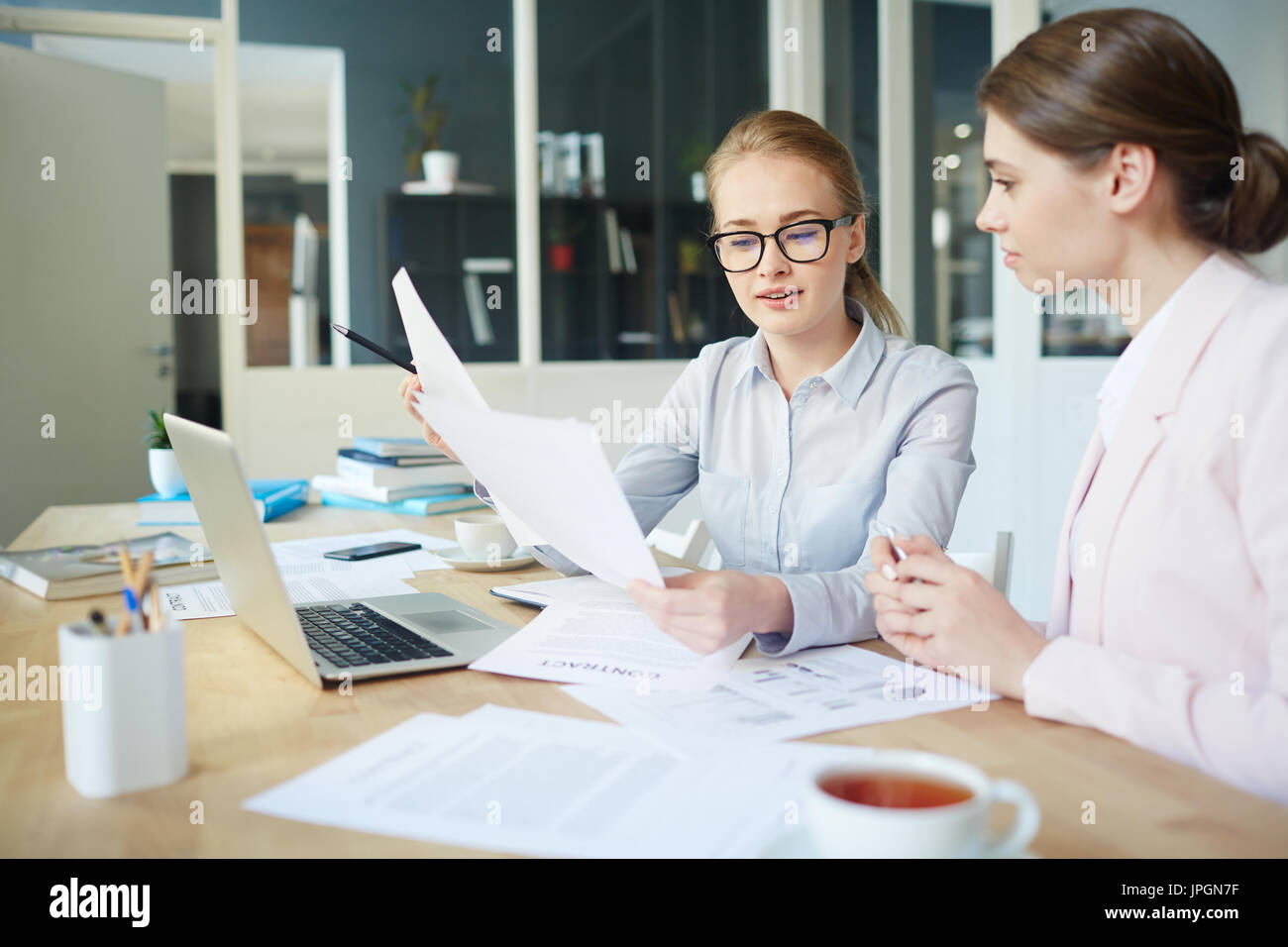 Young teachers discussing paperwork of their students while checking ...
