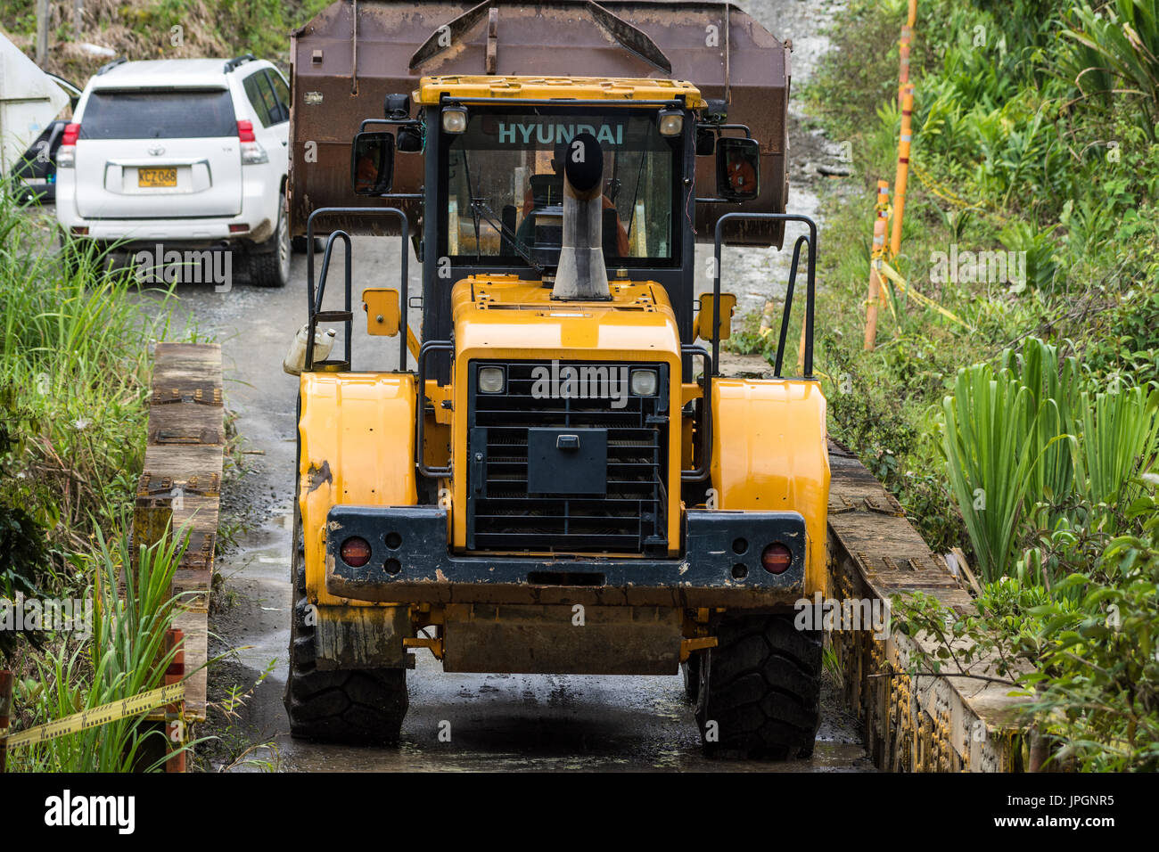 A heavy-duty bulldozer driving over a narrow bridge. Colombia, South ...