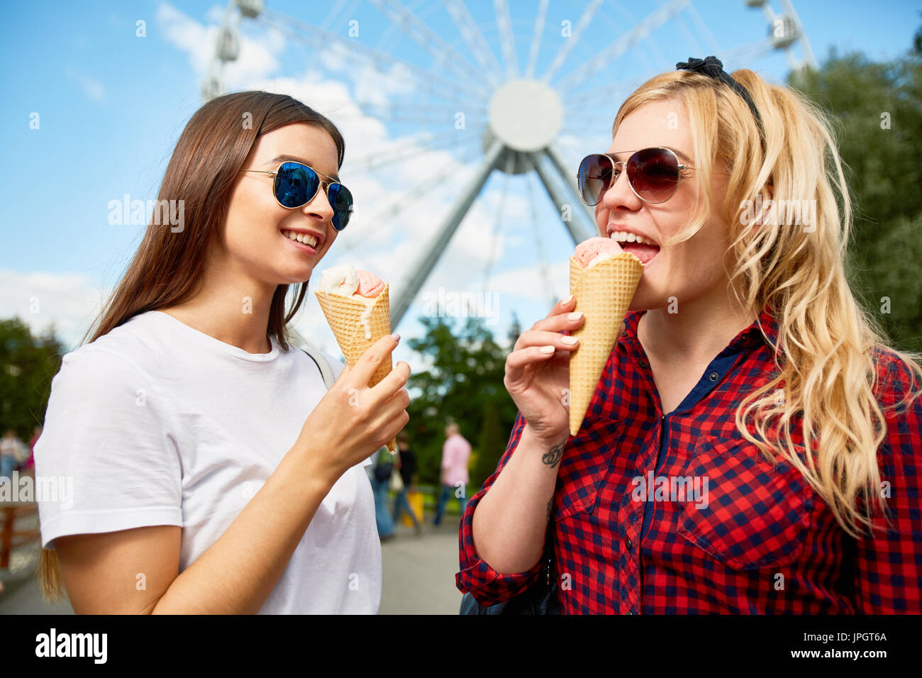 Portrait Of Two Beautiful Young Women Enjoying Ice Cream Cones In