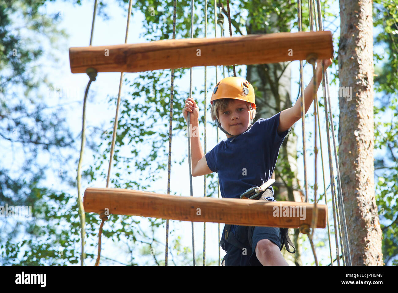 Child boy enjoys climbing in the ropes course adventure. Child engaged ...