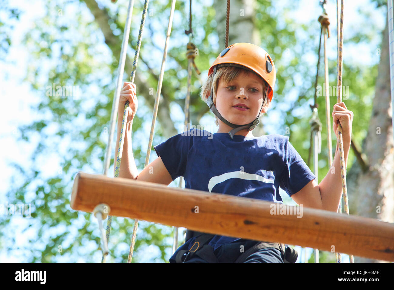 Child boy enjoys climbing in the ropes course adventure. Child engaged ...