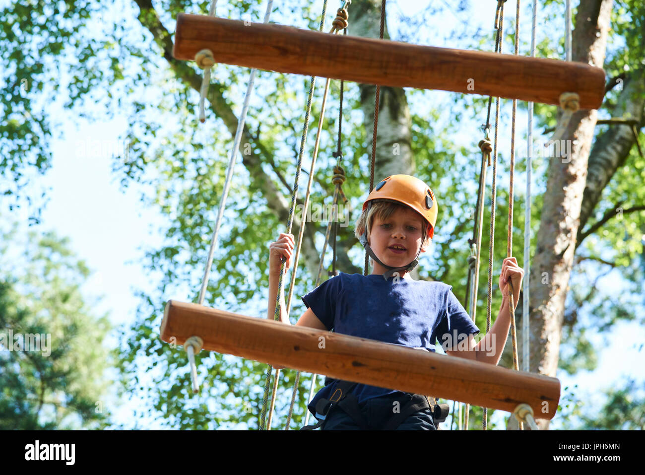 Child boy enjoys climbing in the ropes course adventure. Child engaged ...