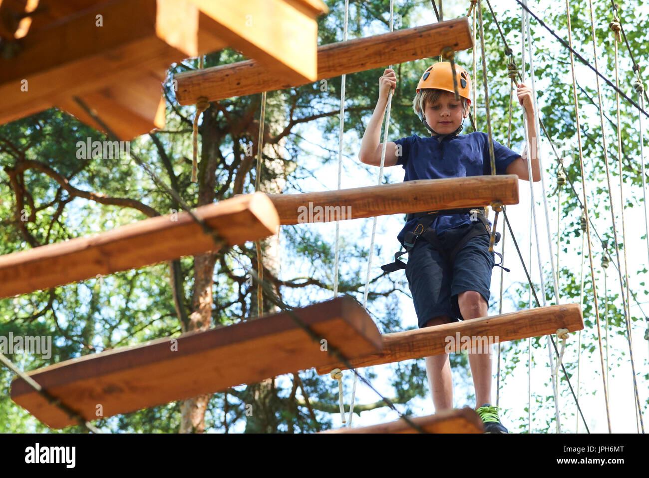 Child boy enjoys climbing in the ropes course adventure. Child engaged ...