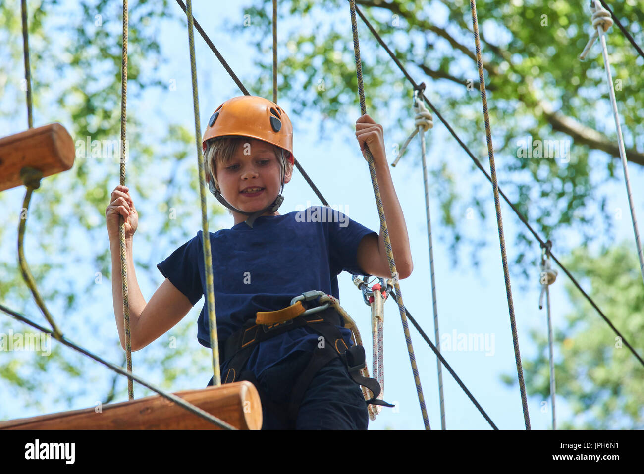 Child boy enjoys climbing in the ropes course adventure. Child engaged ...
