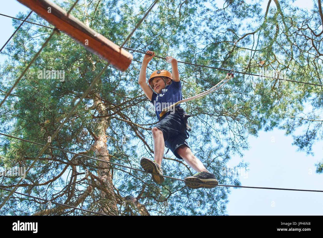 Child boy enjoys climbing in the ropes course adventure. Child engaged ...