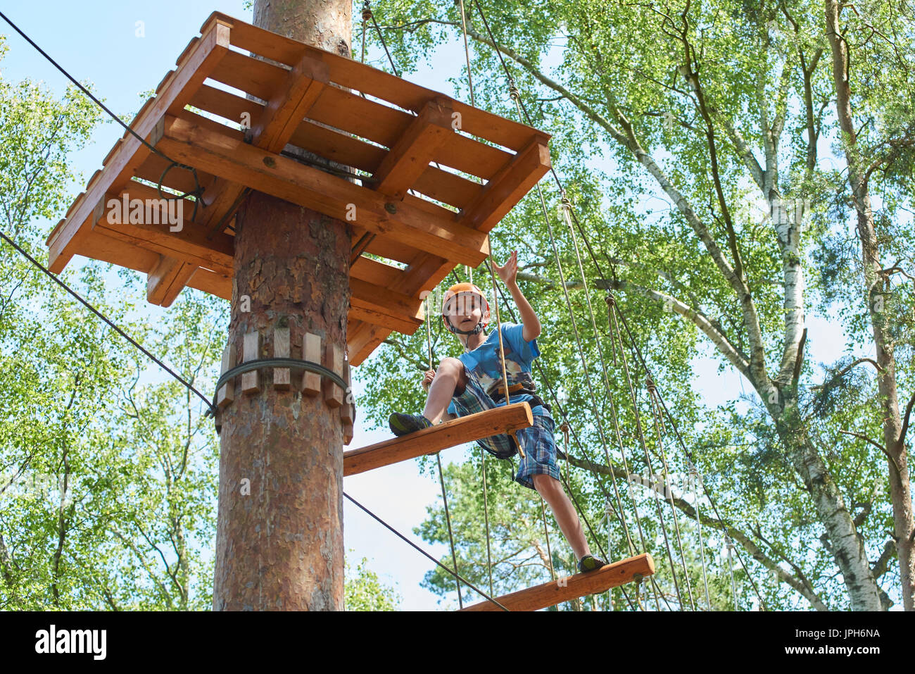 Child boy enjoys climbing in the ropes course adventure. Child engaged ...