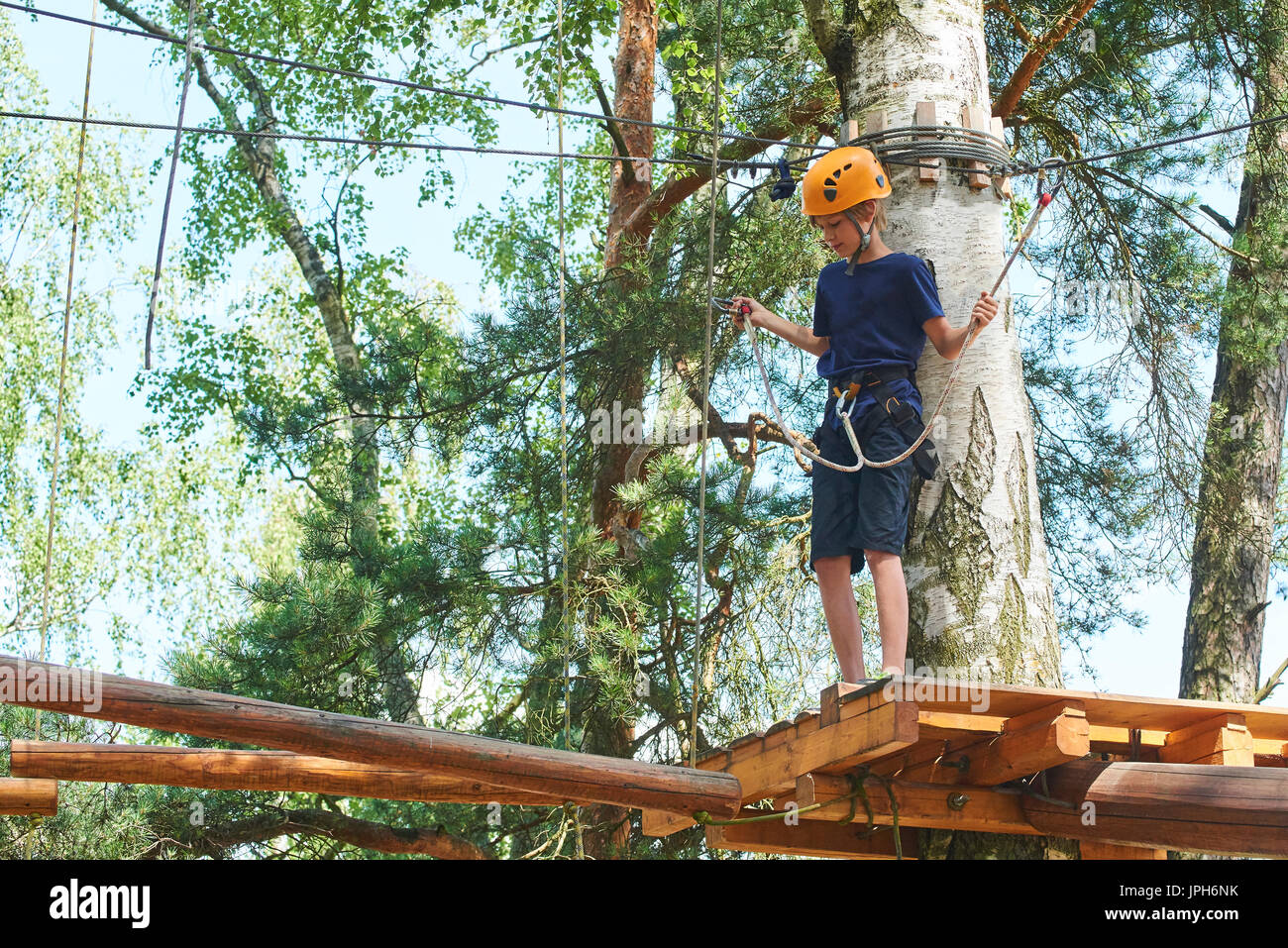 Child boy enjoys climbing in the ropes course adventure. Child engaged ...