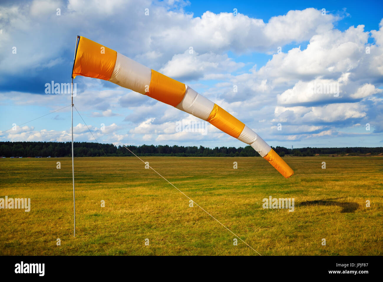 Windsock at small airfield. Blue sky with clouds and field of grass ...