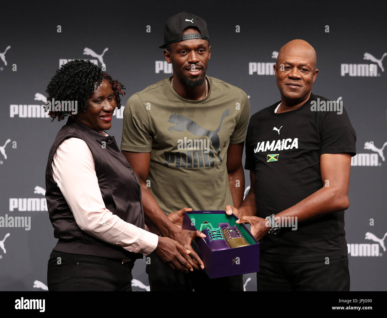 Usain Bolt shows his running shoes with his parents, Jennifer (left ...