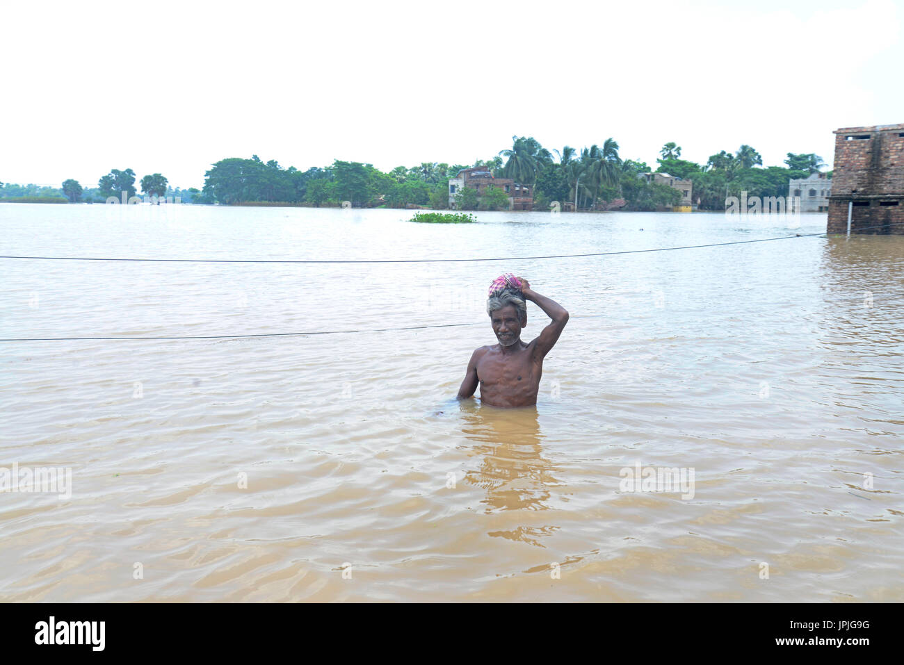 Amta, India. 01st Aug, 2017. Old man wades through chest deep water to ...