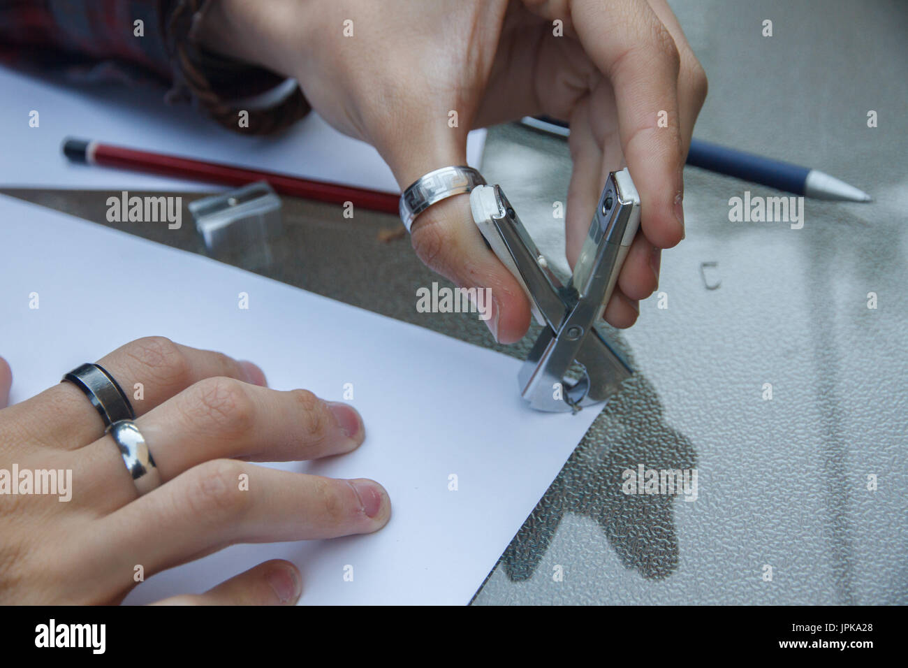 Photo of close up of a hands removing a staple from some documents with ...