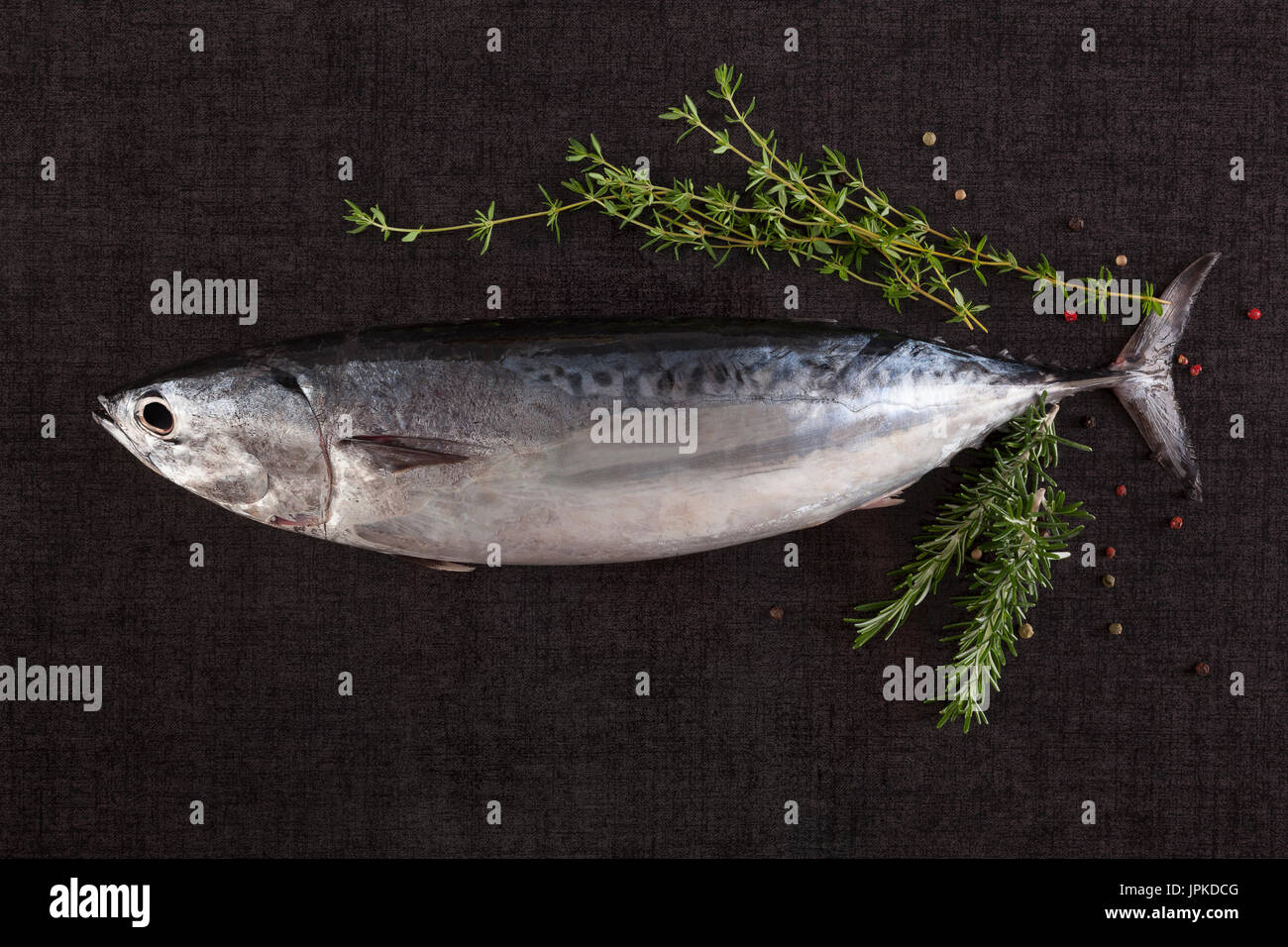 Fresh tuna fish with rosemary and thyme on black table top view ...