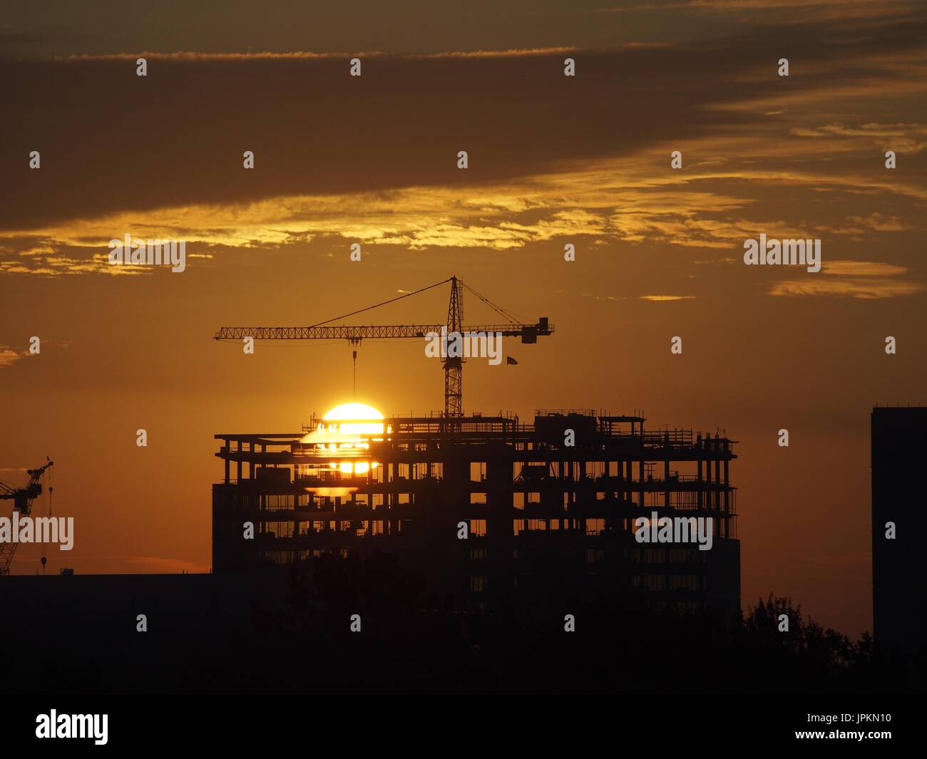 Sun rising behind new building Stock Photo - Alamy