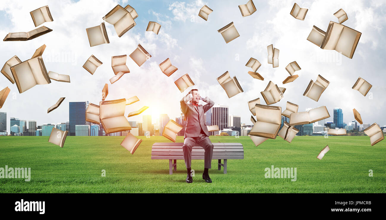 Many old books falling from above and student guy sitting on bench ...