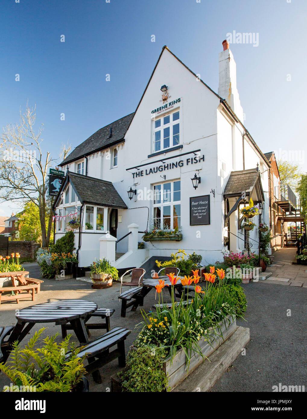 Historic white painted pub, The Laughing Fish, with outdoor dining area ...