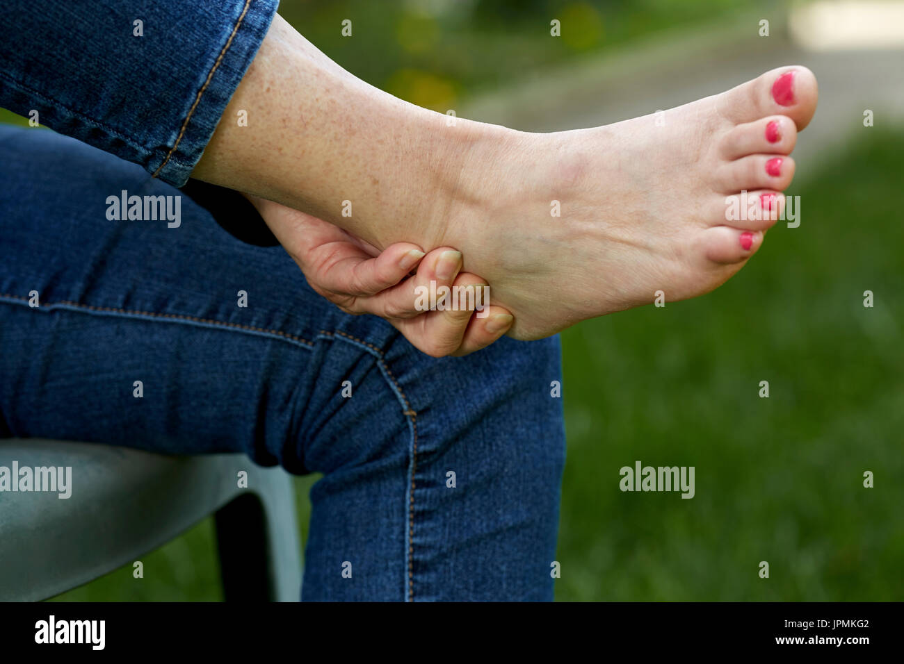 A woman's hand holding the heel of her foot while sitting in a chair ...