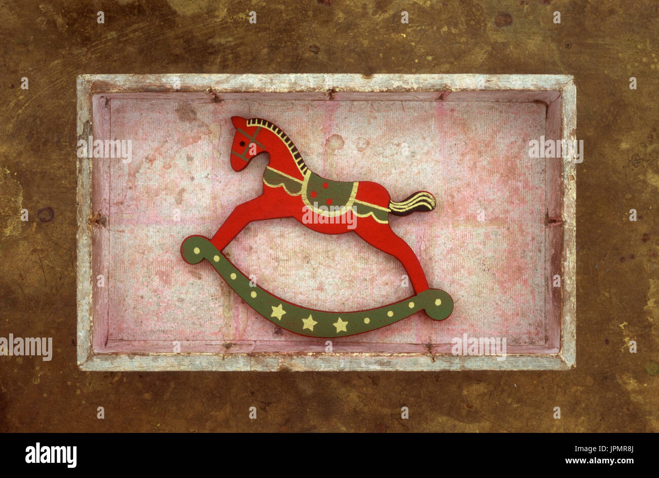 Small red green and gold wooden rocking horse model lying in shallow ...