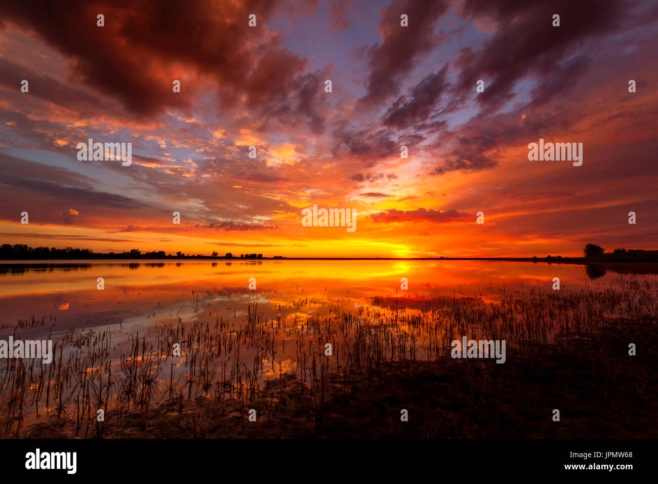 Strong vivid sunrise or a sunset reflecting in the waters of a lake ...